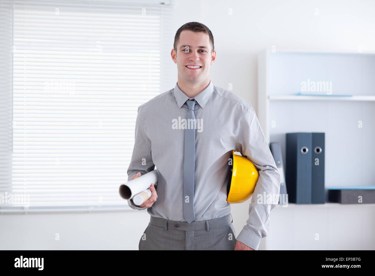 Architect carrying helm and plans Stock Photo - Alamy