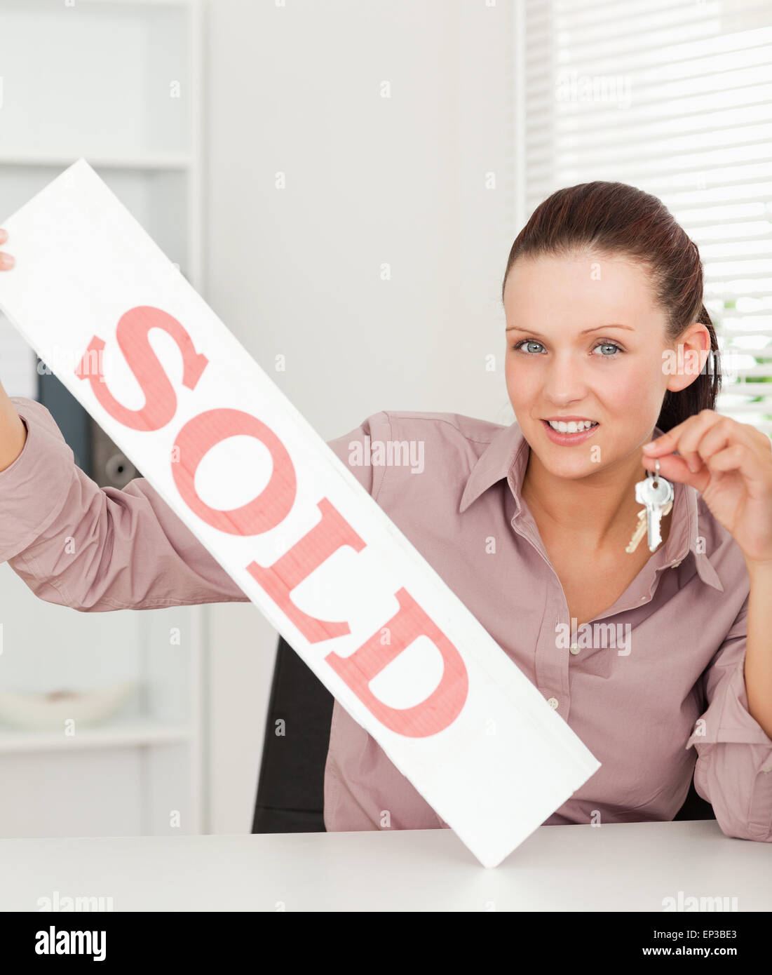 Businesswoman holding keys and sold sign Stock Photo - Alamy