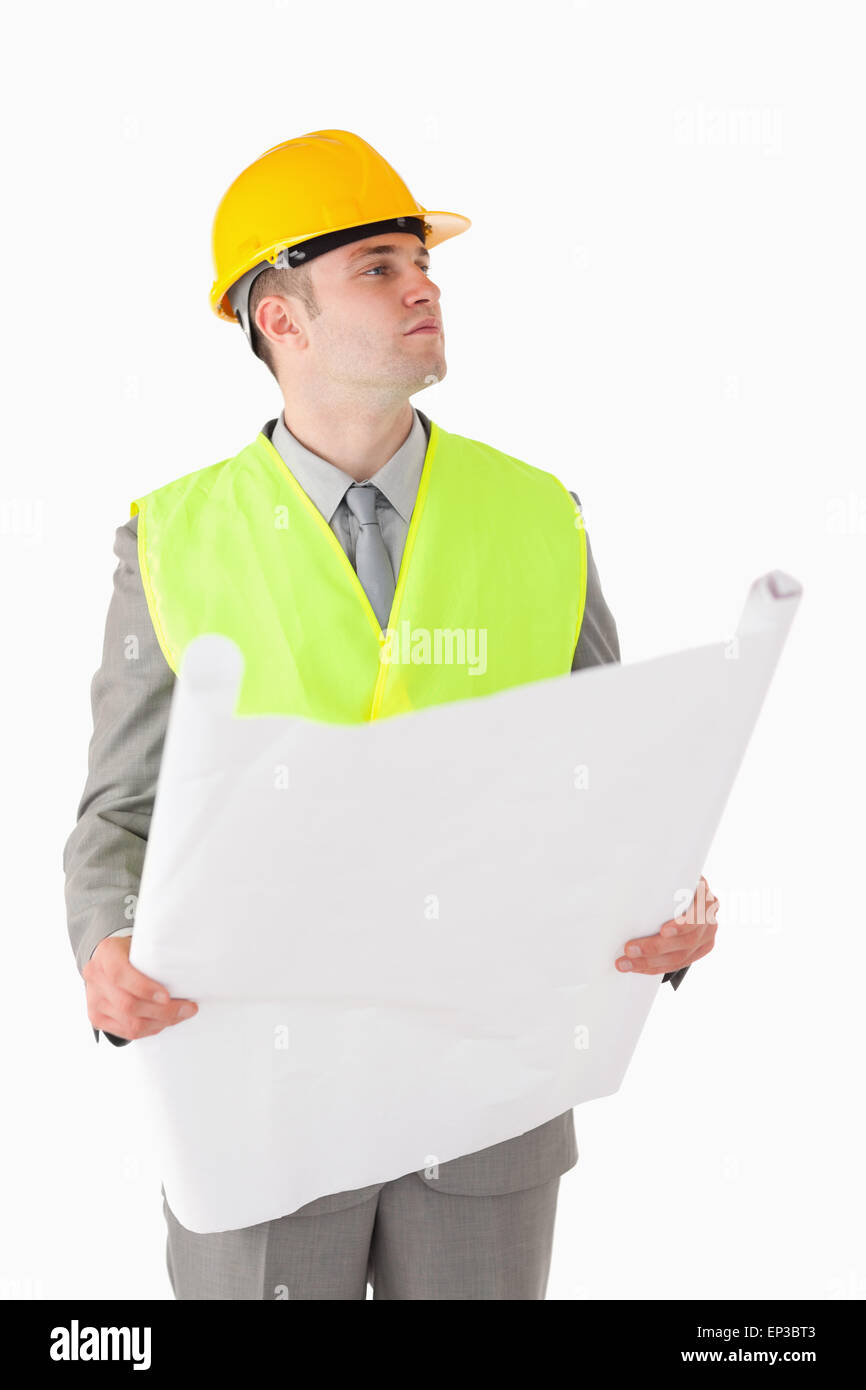 Portrait of a young builder looking around while holding a plan Stock ...