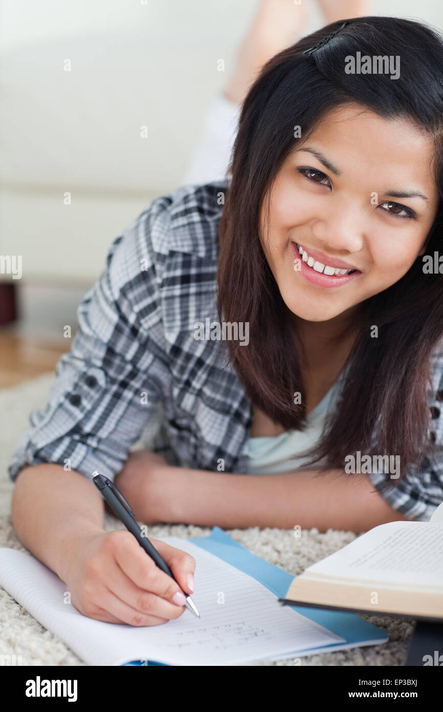 Smiling woman on the floor writing on a notebook Stock Photo - Alamy
