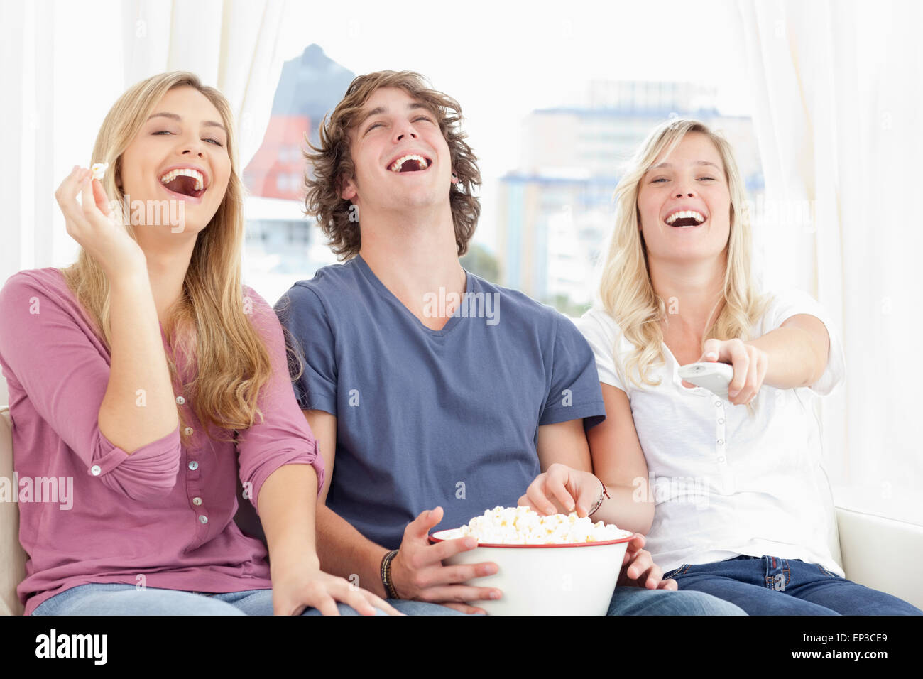 Three friends eating popcorn while laughing at the show Stock Photo - Alamy