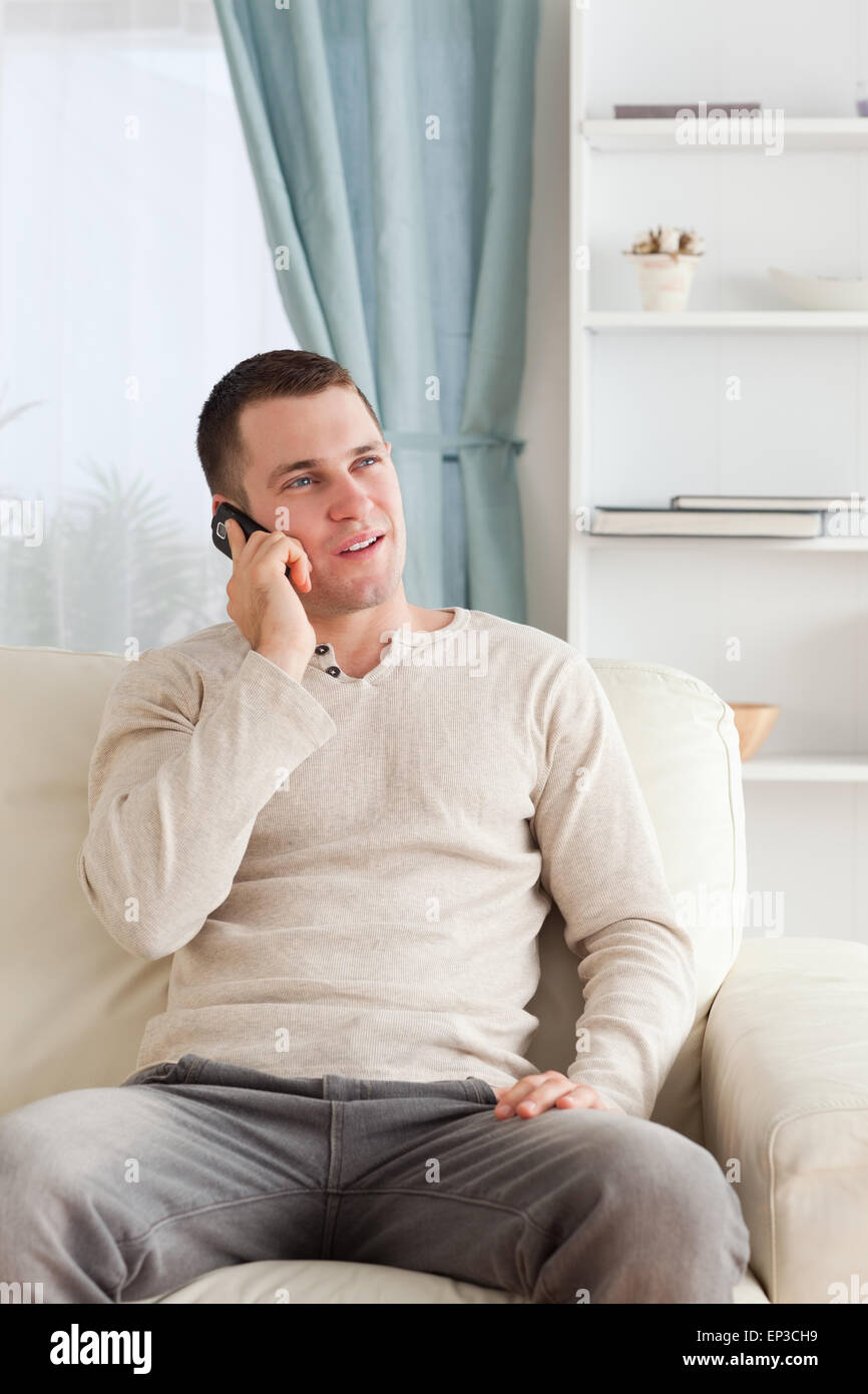 Portrait of a young man on the phone while sitting on his sofa Stock ...
