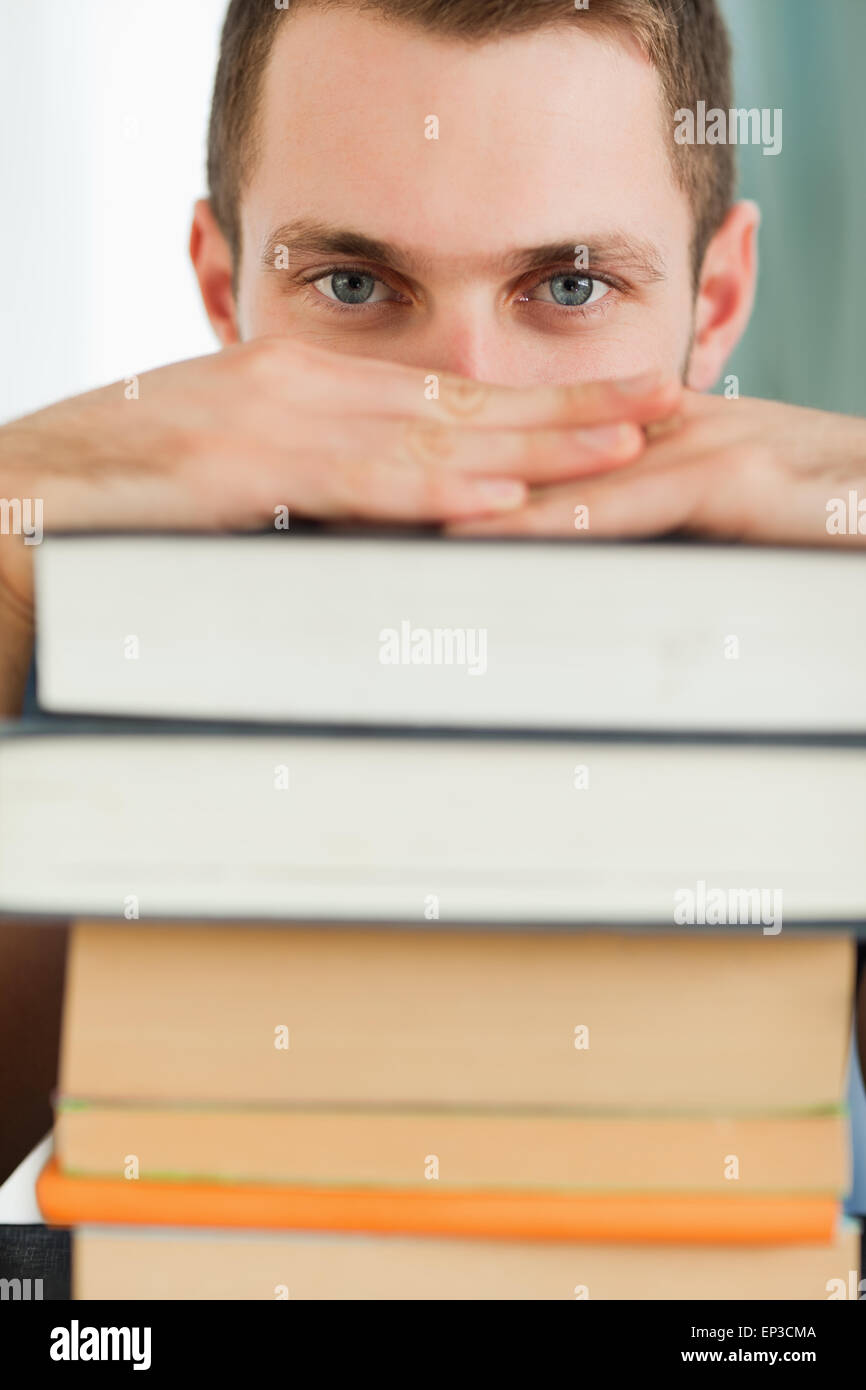 Close up of student hiding behind a pile of books Stock Photo - Alamy