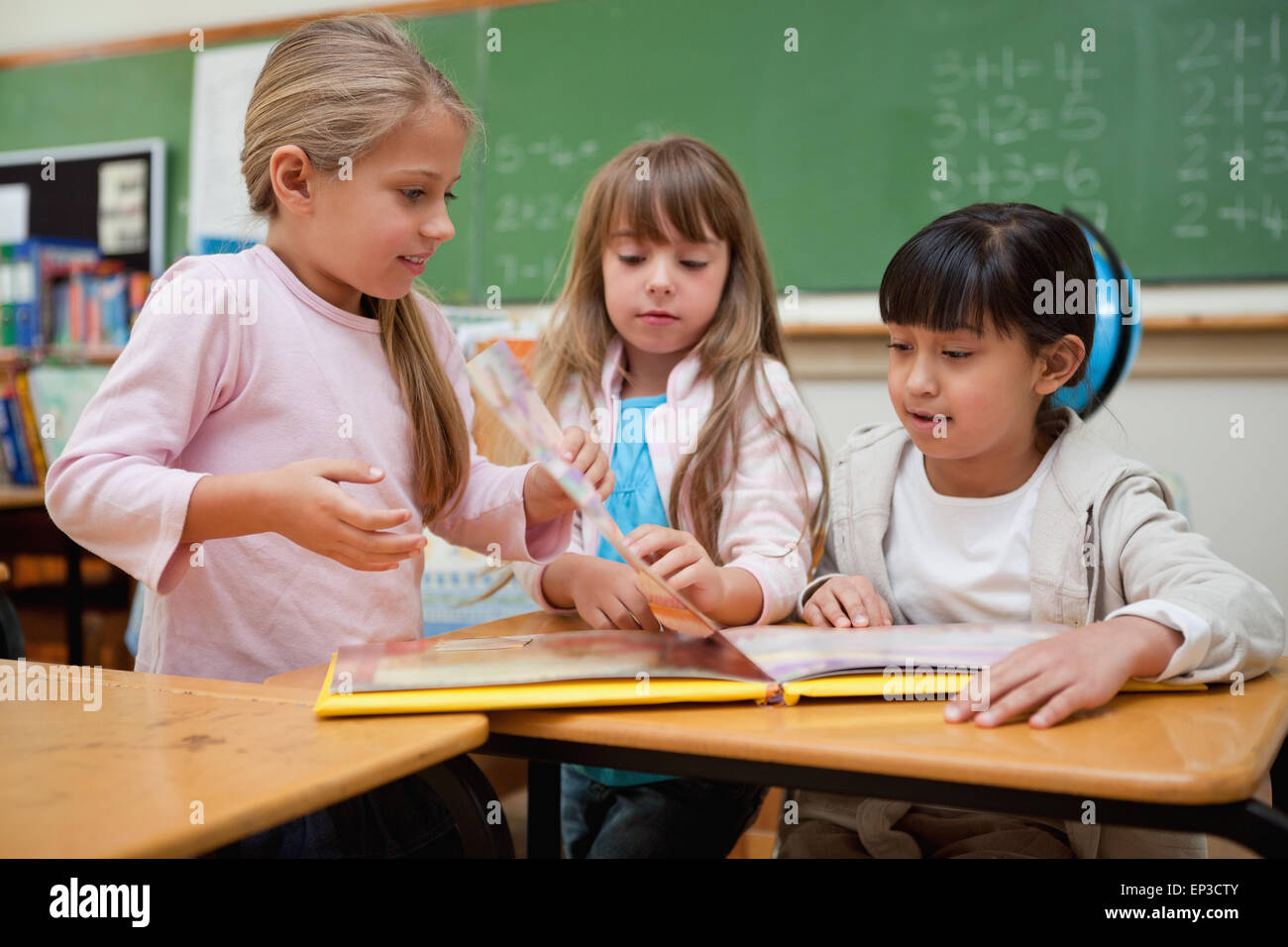 Little schoolgirls reading a fairy tale to their classmate Stock Photo ...
