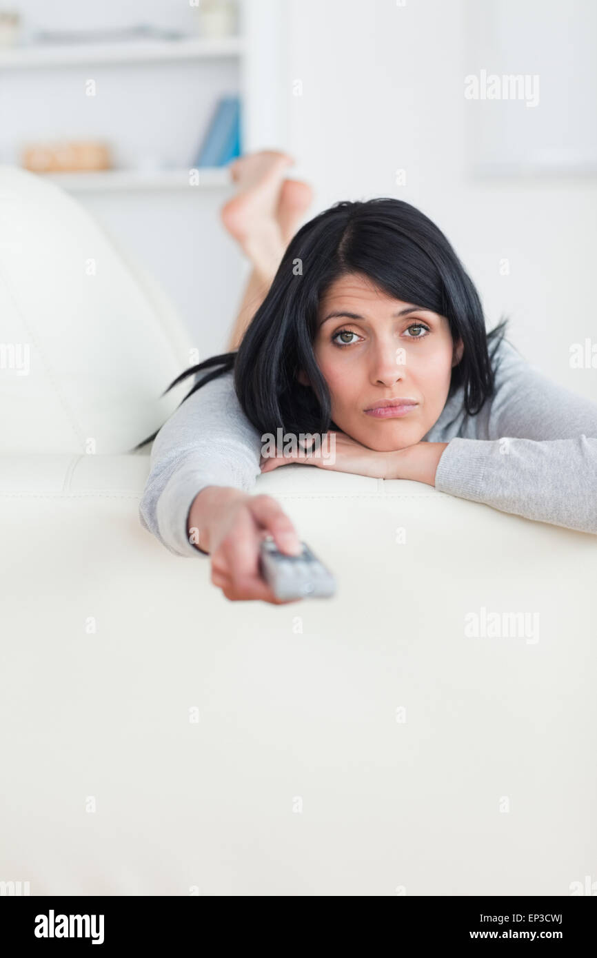 Woman pressing on a television remote while laying on a sofa Stock ...