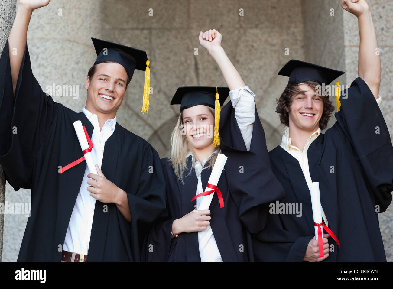 Graduates holding their diploma while raising arm Stock Photo - Alamy