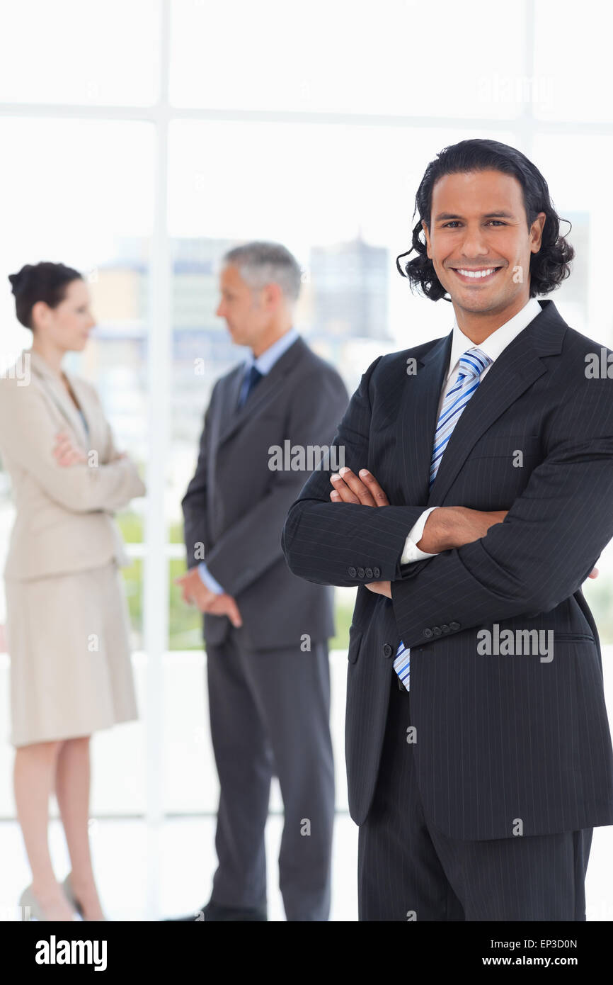 Young smiling executive standing upright in front of two business ...