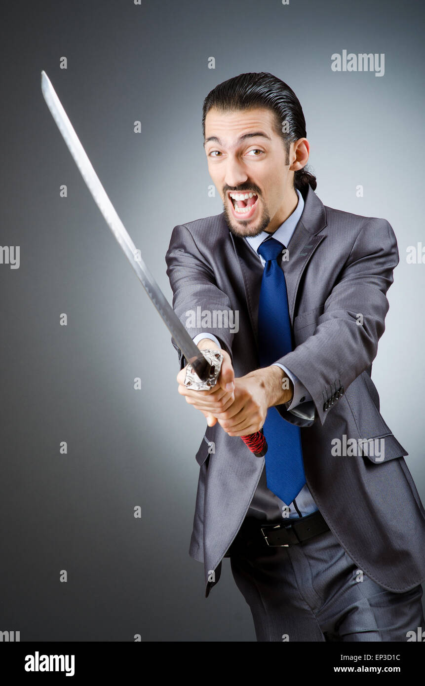 Angry businessman with sword in dark room Stock Photo - Alamy