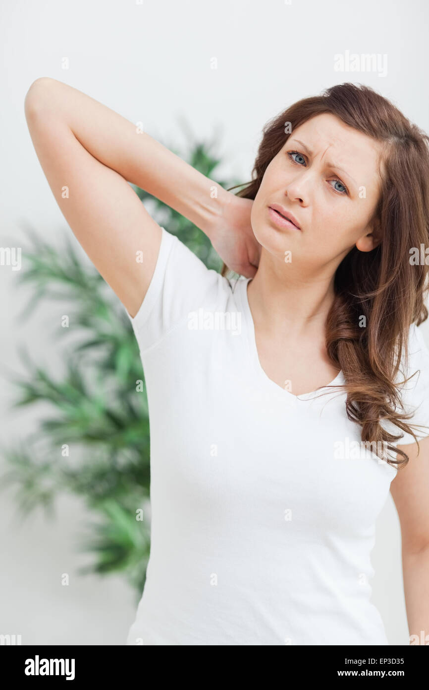 brunette standing while placing her hand on her neck Stock Photo - Alamy