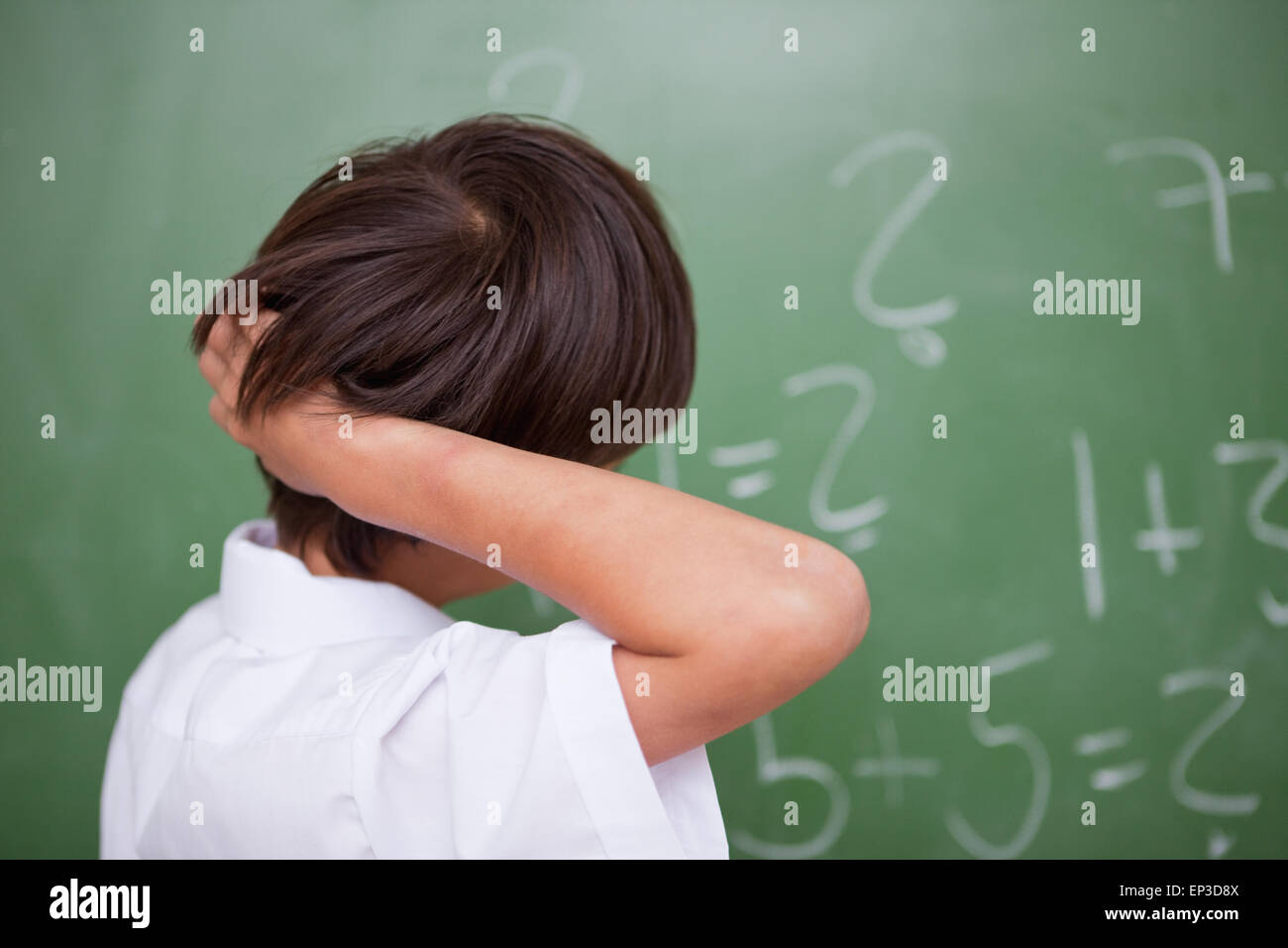 Schoolboy thinking while scratching the back of his head Stock Photo ...