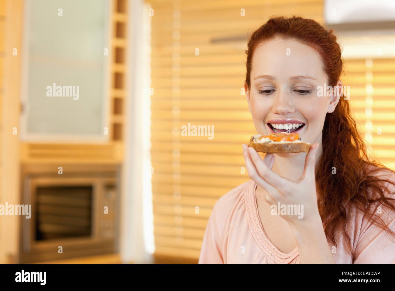 Woman eating a slice of bread in the kitchen Stock Photo - Alamy