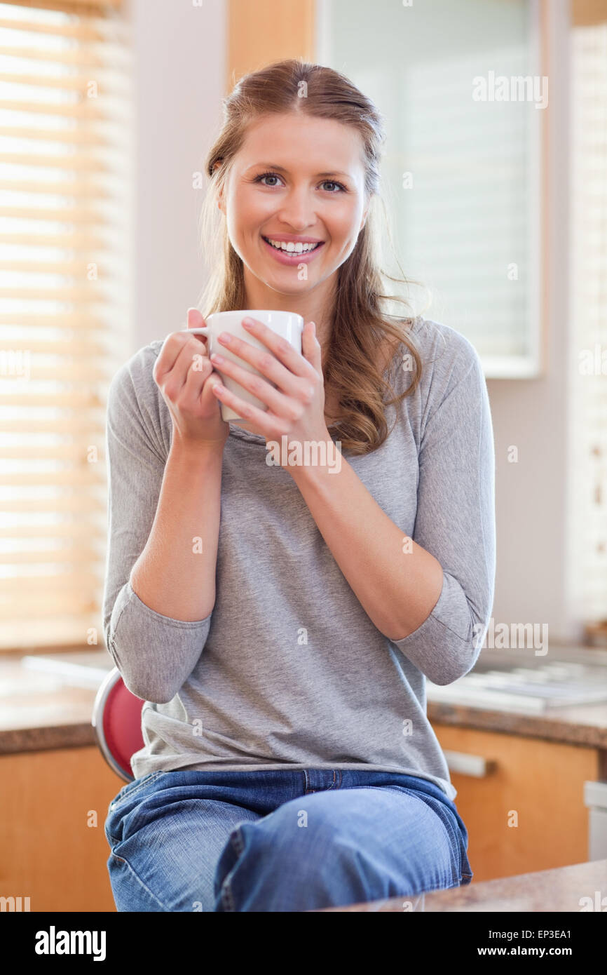 Smiling woman having a cup of coffee in the kitchen Stock Photo - Alamy