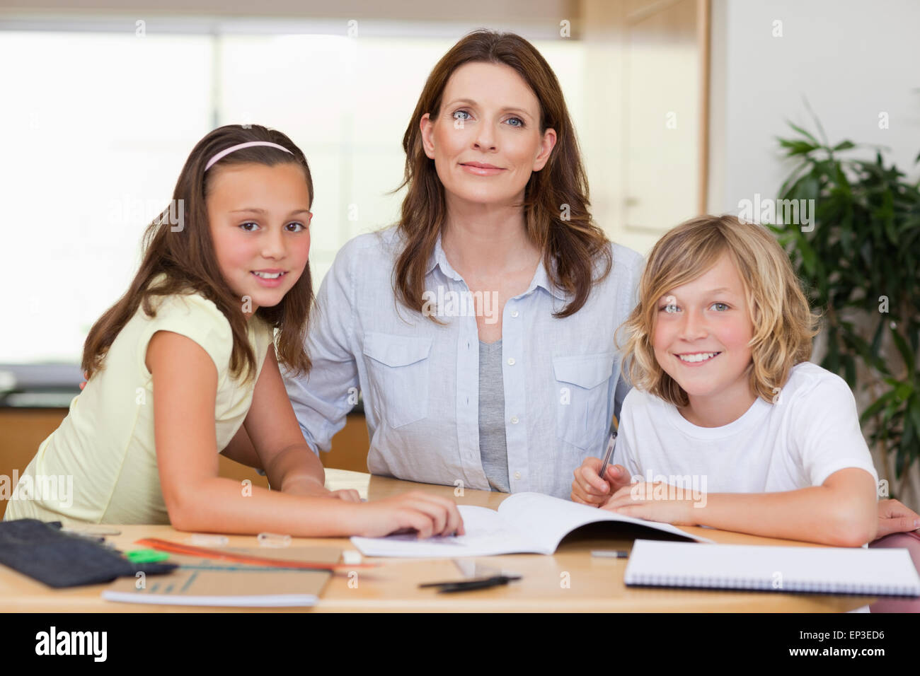 Woman helping her children with homework Stock Photo - Alamy