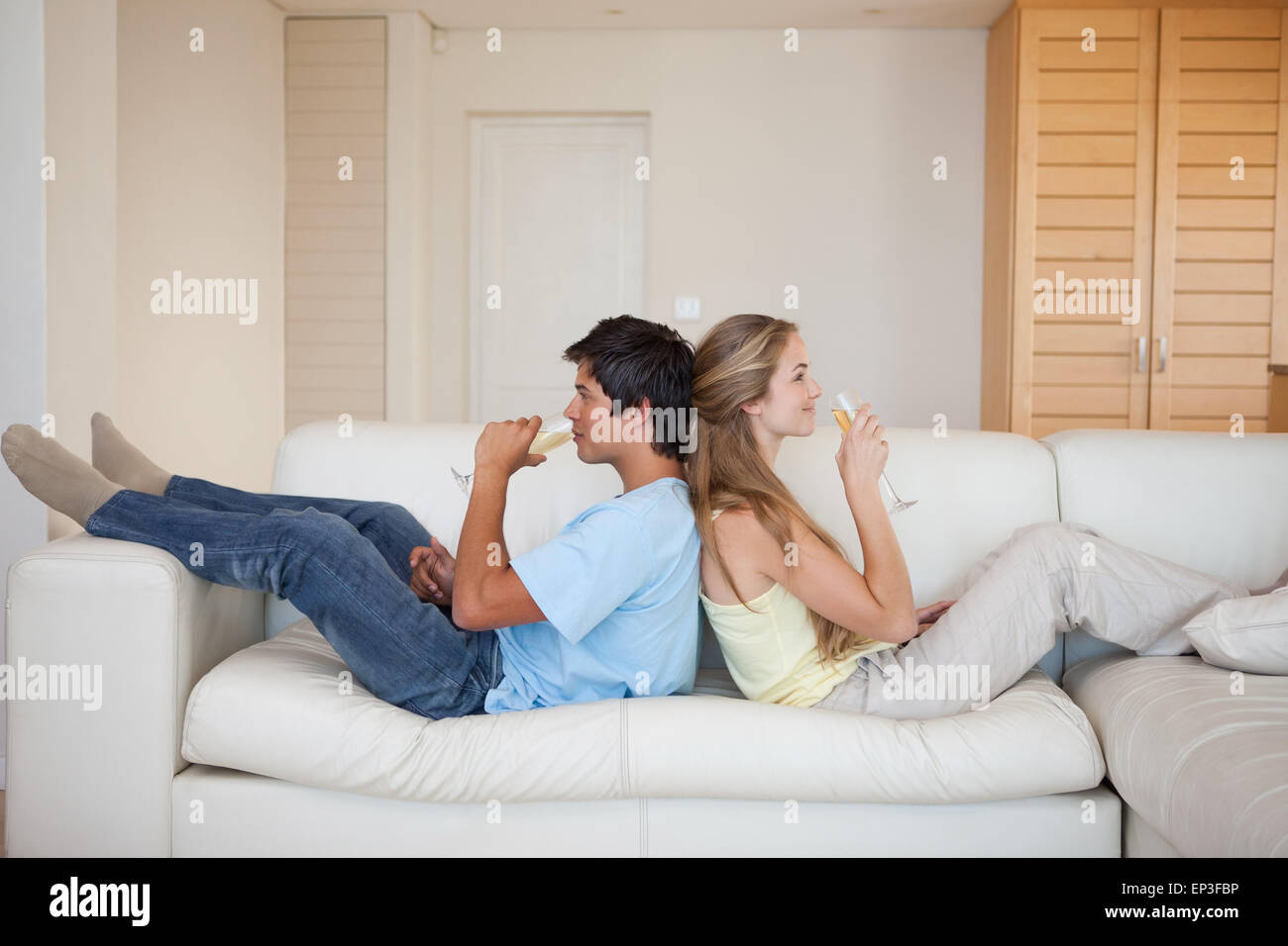 Couple sitting back to back while drinking wine Stock Photo - Alamy