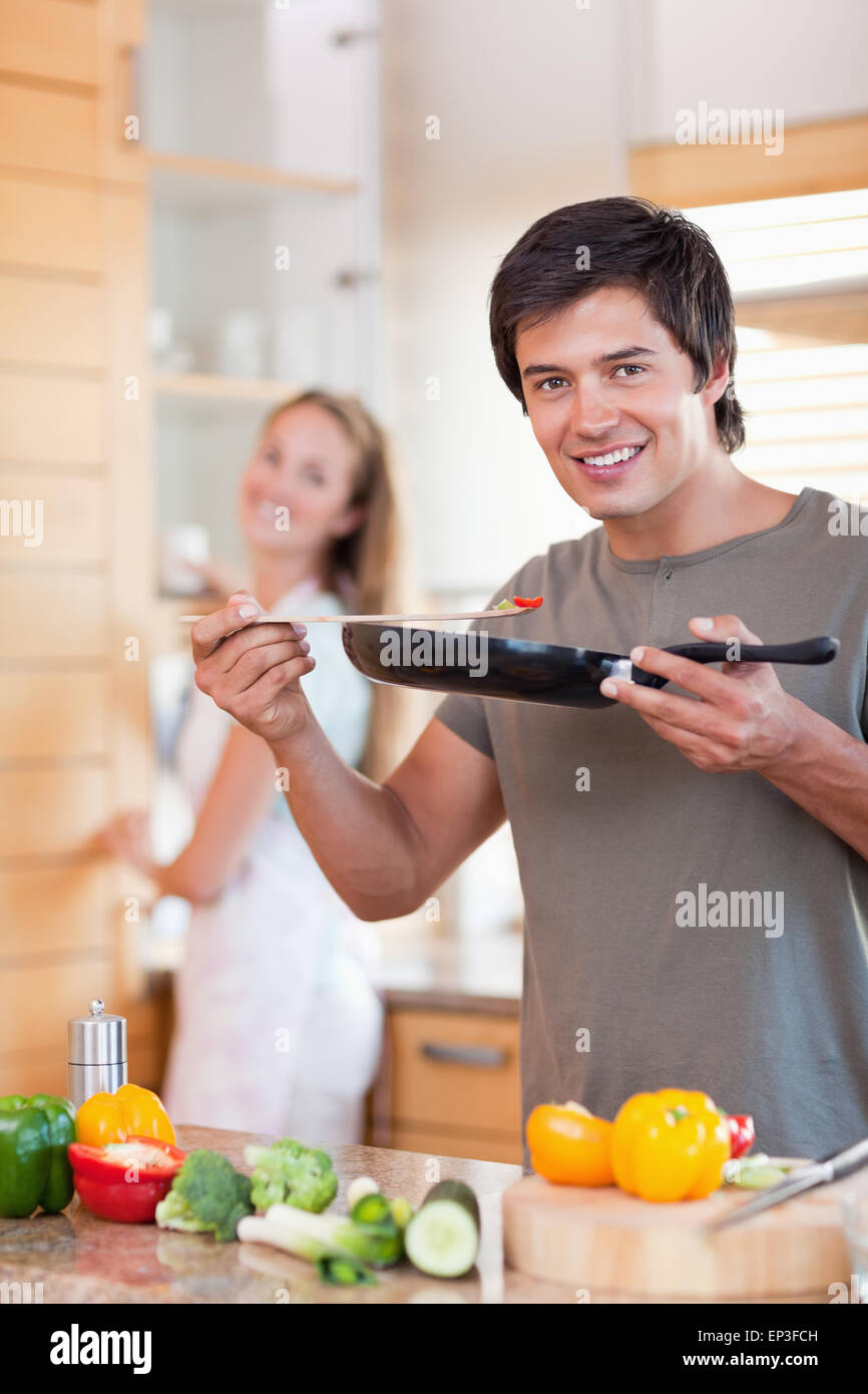 Portrait of a young man cooking while his wife is washing the di Stock ...