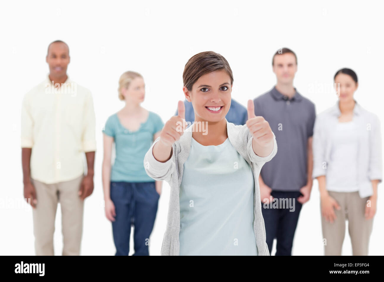 Close-up of a woman smiling giving the thumbs-up with people behind ...