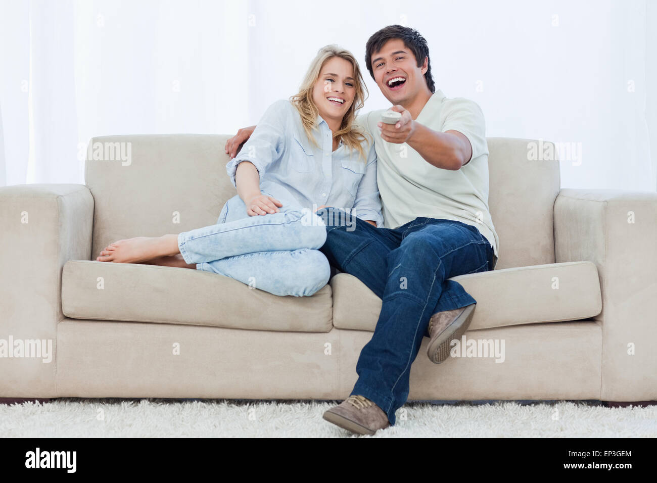 A young couple are sitting down looking at the camera and laughing ...