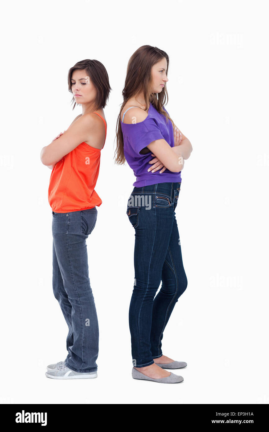 Two girls standing back to back with their arms crossed Stock Photo - Alamy