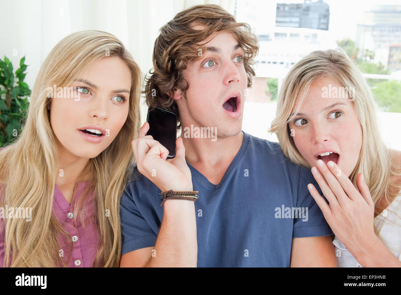 Three shocked friends listening to a phone conversation Stock Photo - Alamy