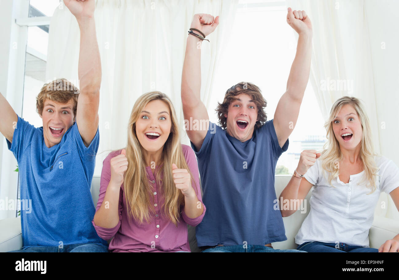 Excited celebrating friends sit together as they look at the camera ...