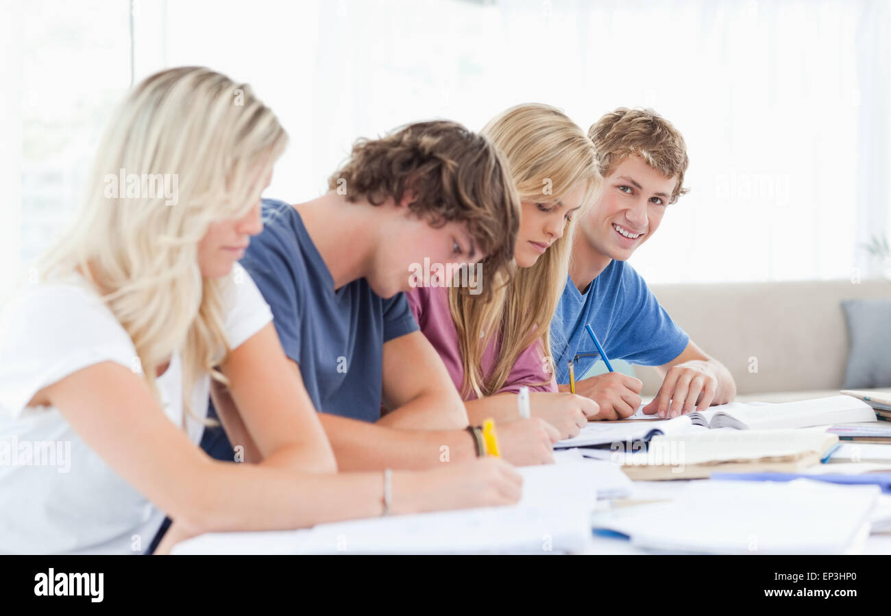 A group of students working as one student looks at the camera while ...