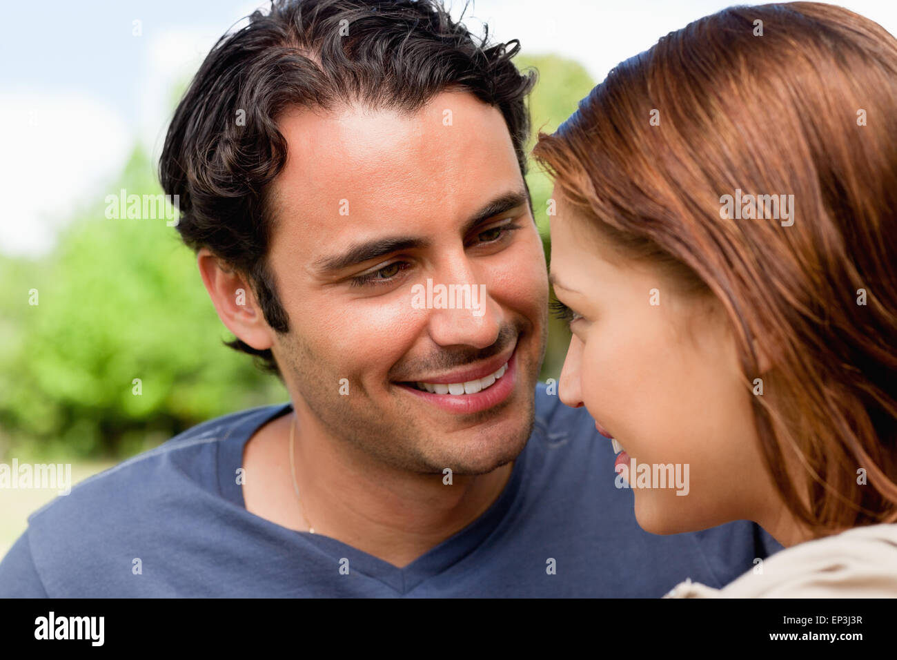 Two friends laughing while they are both sitting together on the grass ...