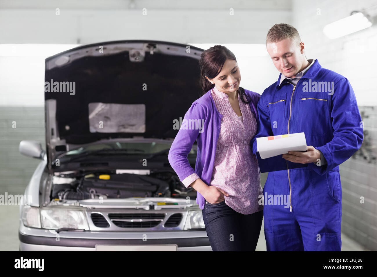 Mechanic showing a paper in a clipboard to a woman Stock Photo - Alamy