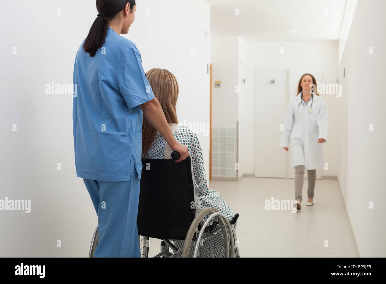 Nurse pushing patient in wheelchair with doctor approaching Stock Photo ...
