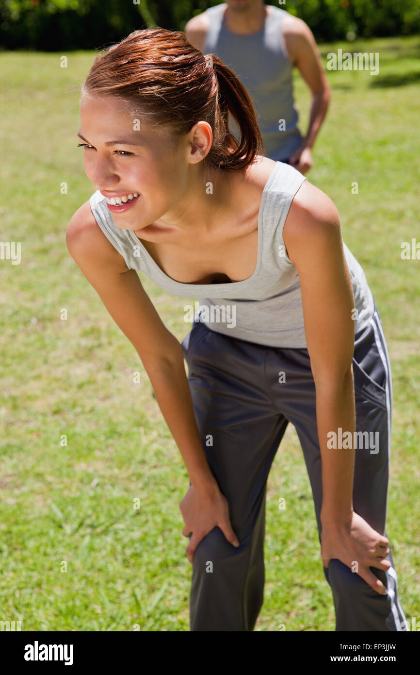 Smiling woman bending over while a man is walkng behind her Stock Photo ...
