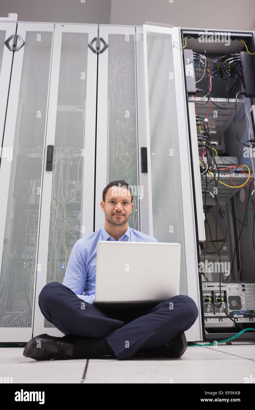 Man sitting in front of servers with his laptop Stock Photo - Alamy