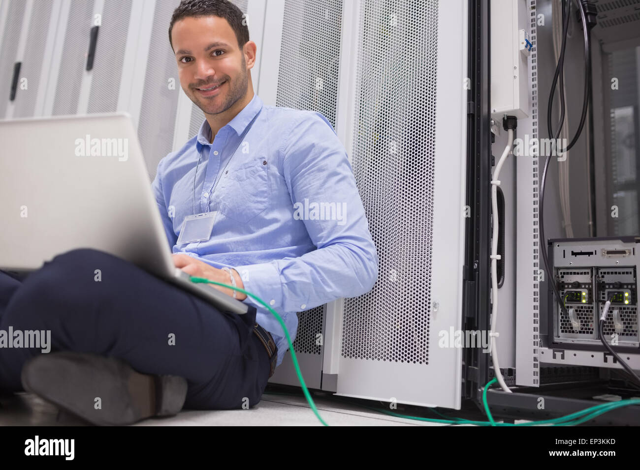 Happy technician working on laptop connected to server Stock Photo - Alamy