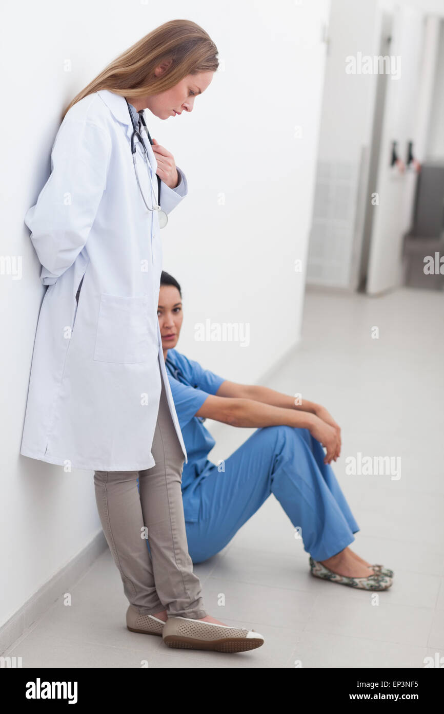 Doctor standing next to a nurse sitting on the floor Stock Photo - Alamy