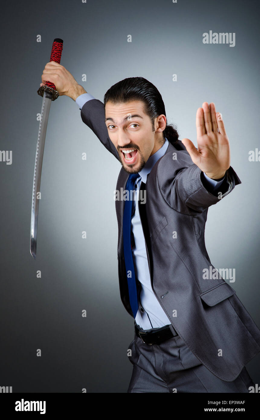 Angry businessman with sword in dark room Stock Photo - Alamy