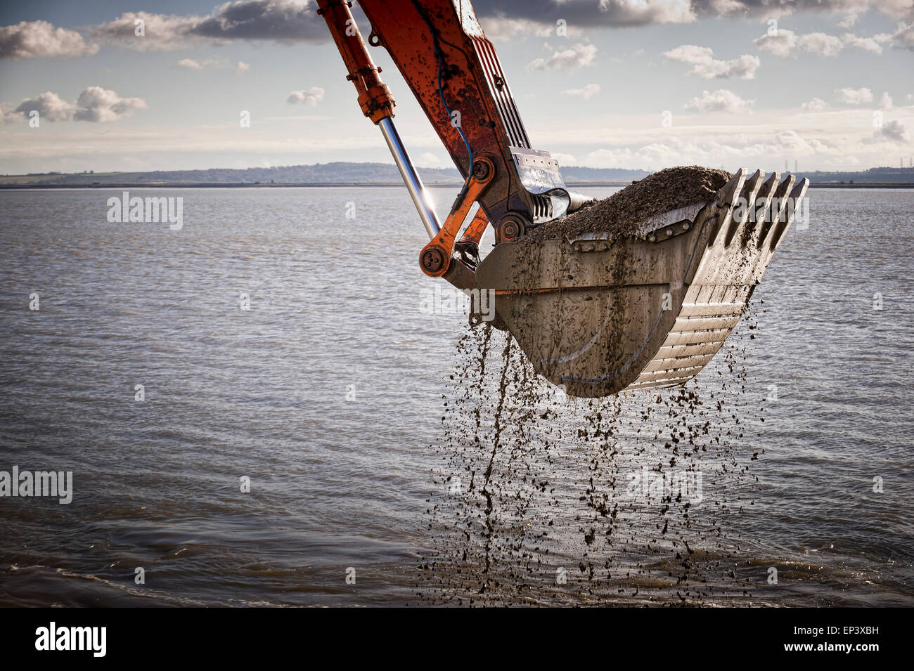 Excavator bucket lifting gravel from the sea Stock Photo - Alamy