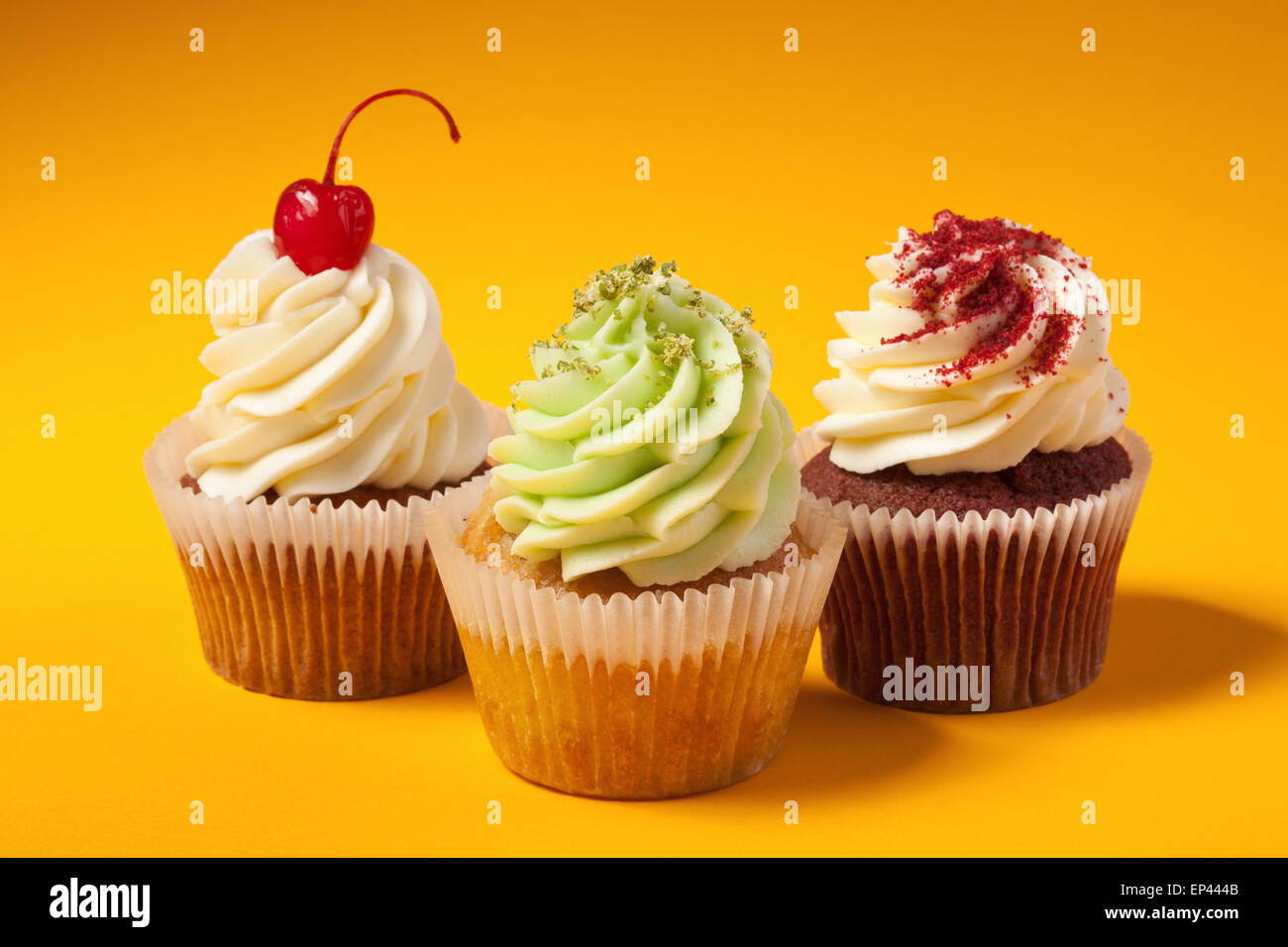 three cupcakes isolated on orange background Stock Photo - Alamy