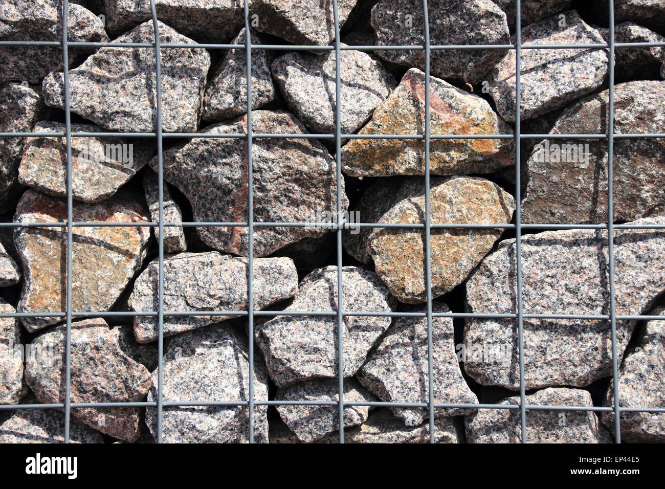 Rocks in solid metal grid wall closeup Stock Photo - Alamy