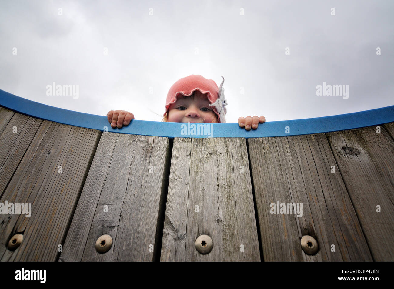 Girl looking down over the edge of a wooden climbing frame Stock Photo ...
