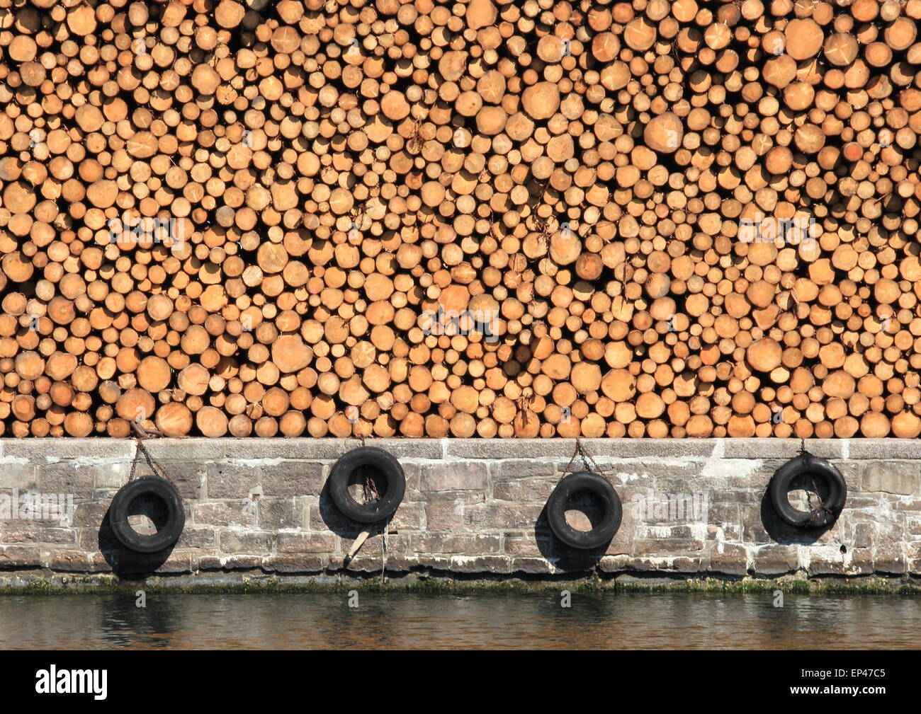 Stack of pinewood timber at pier with tires Stock Photo - Alamy
