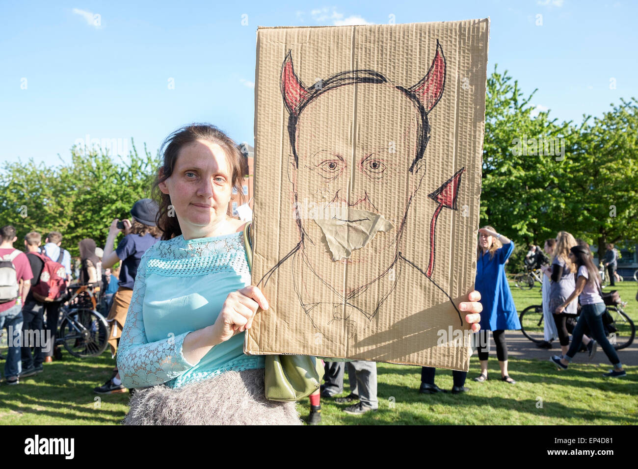 Bristol, UK, 13th May, 2015. A woman holds up a cartoon of David ...