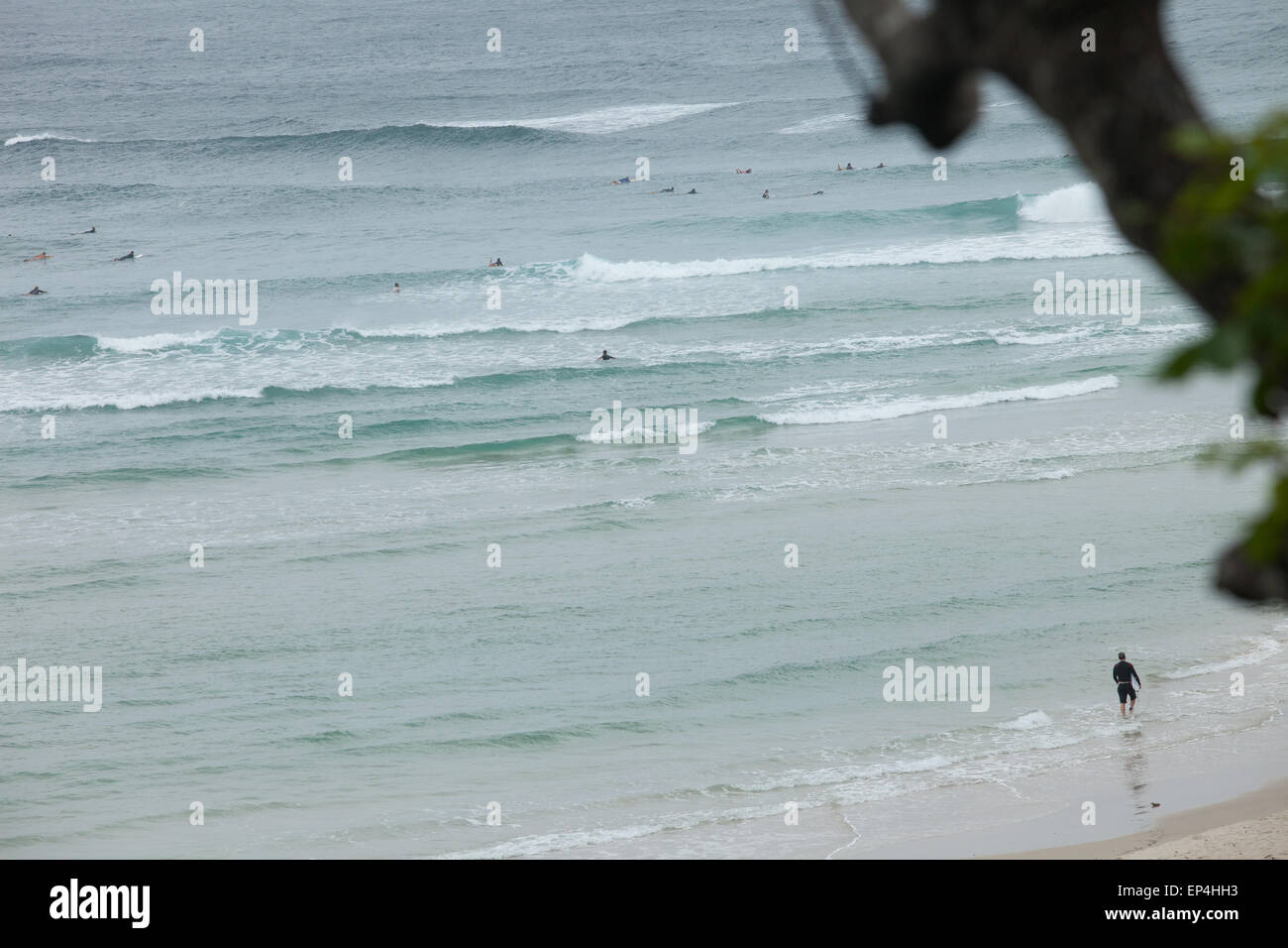 A surfer heading out into a crowded surf spot in Byron Bay, Australia ...