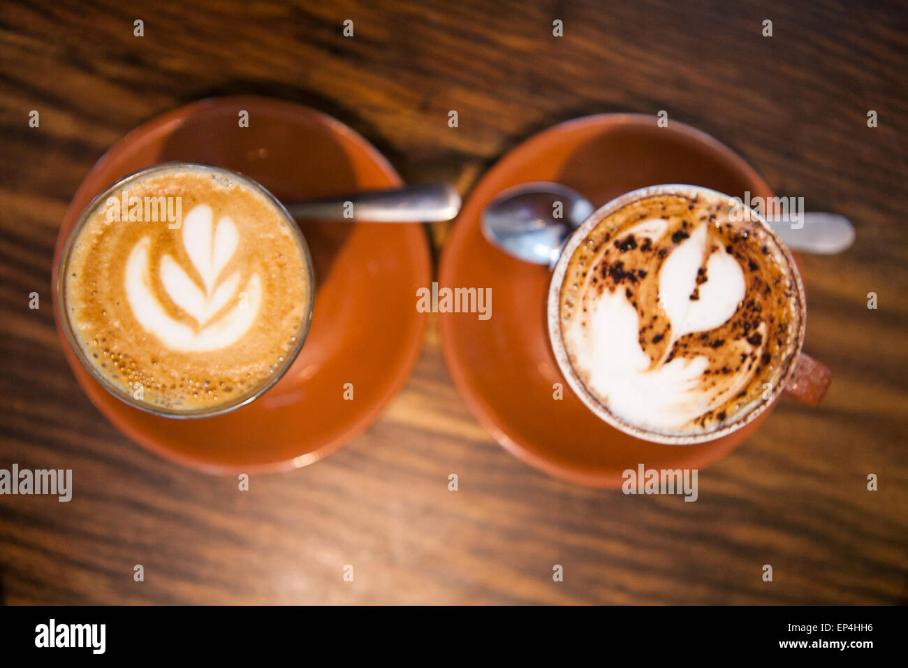 Two lattes with latte art sitting on a wood table Stock Photo - Alamy