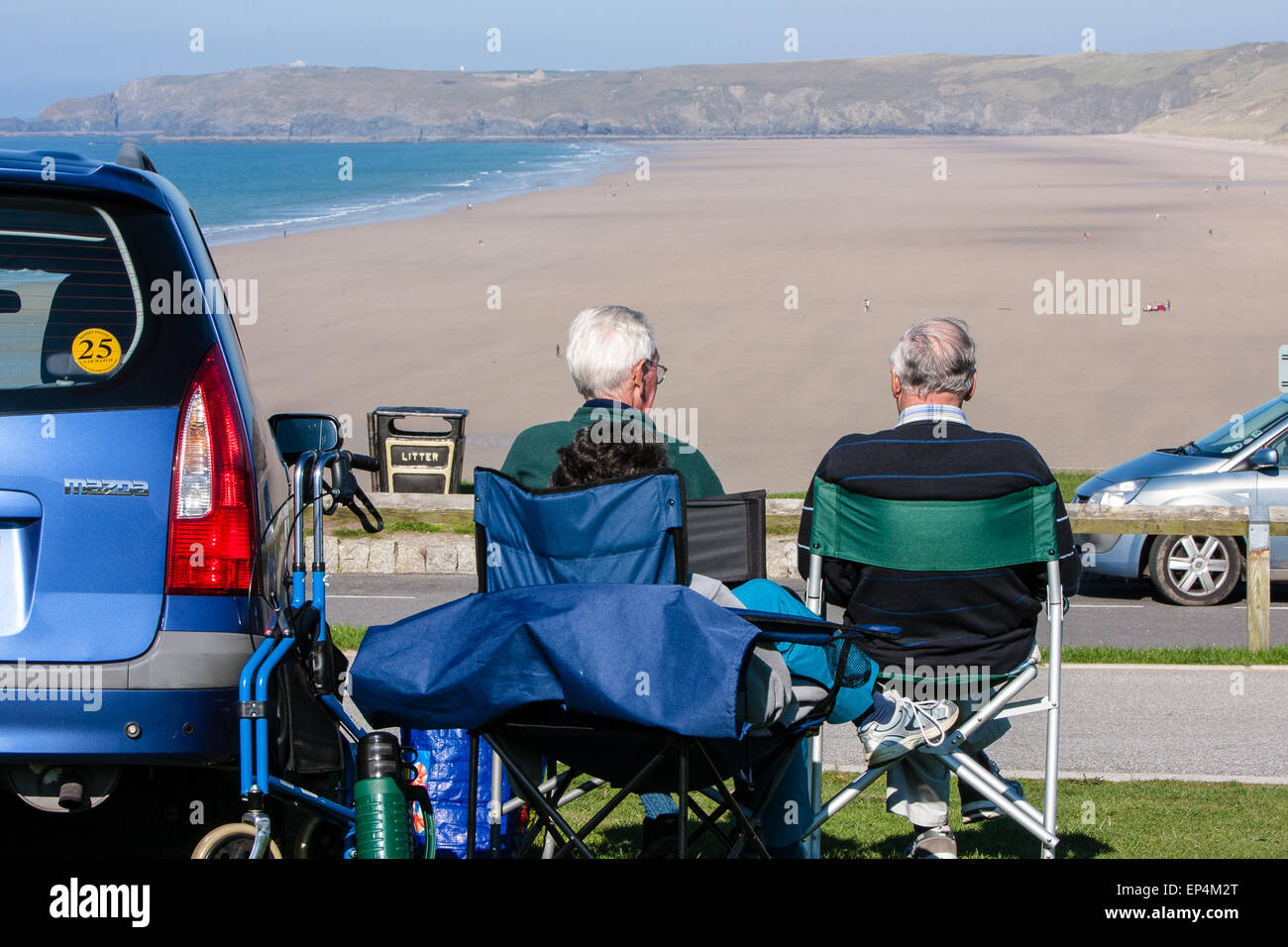 Elderly family sit in the car park next to their car above Perran Sands ...