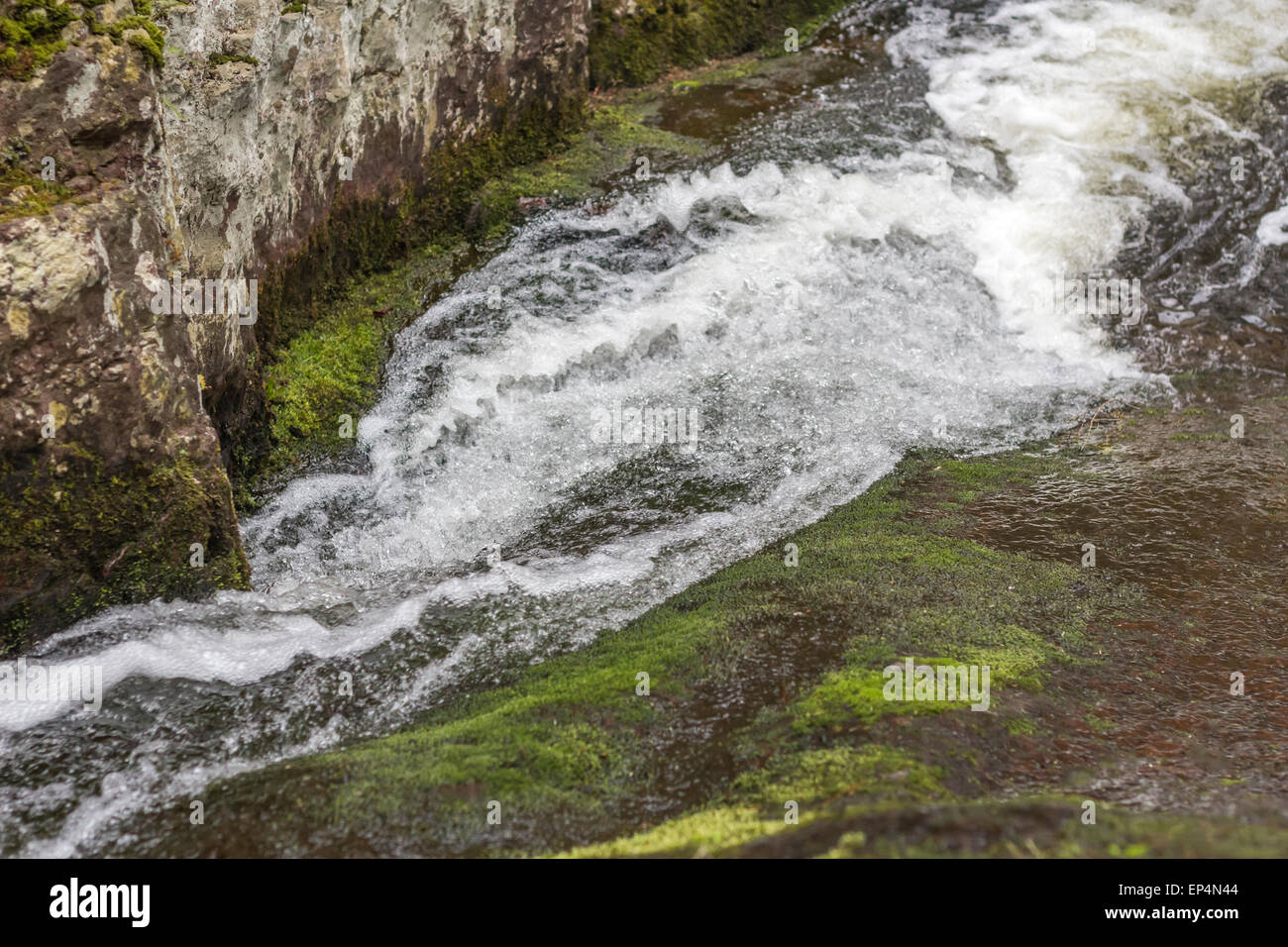 Waterfall rapids with water frozen in time splashing against mossy ...