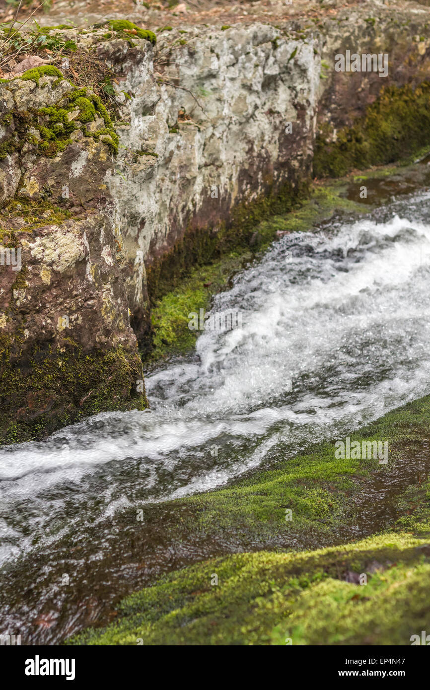 Waterfall rapids with water frozen in time splashing against mossy ...
