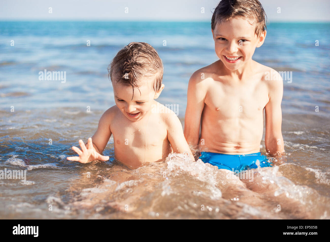 smiling boys sitting on beach Stock Photo - Alamy