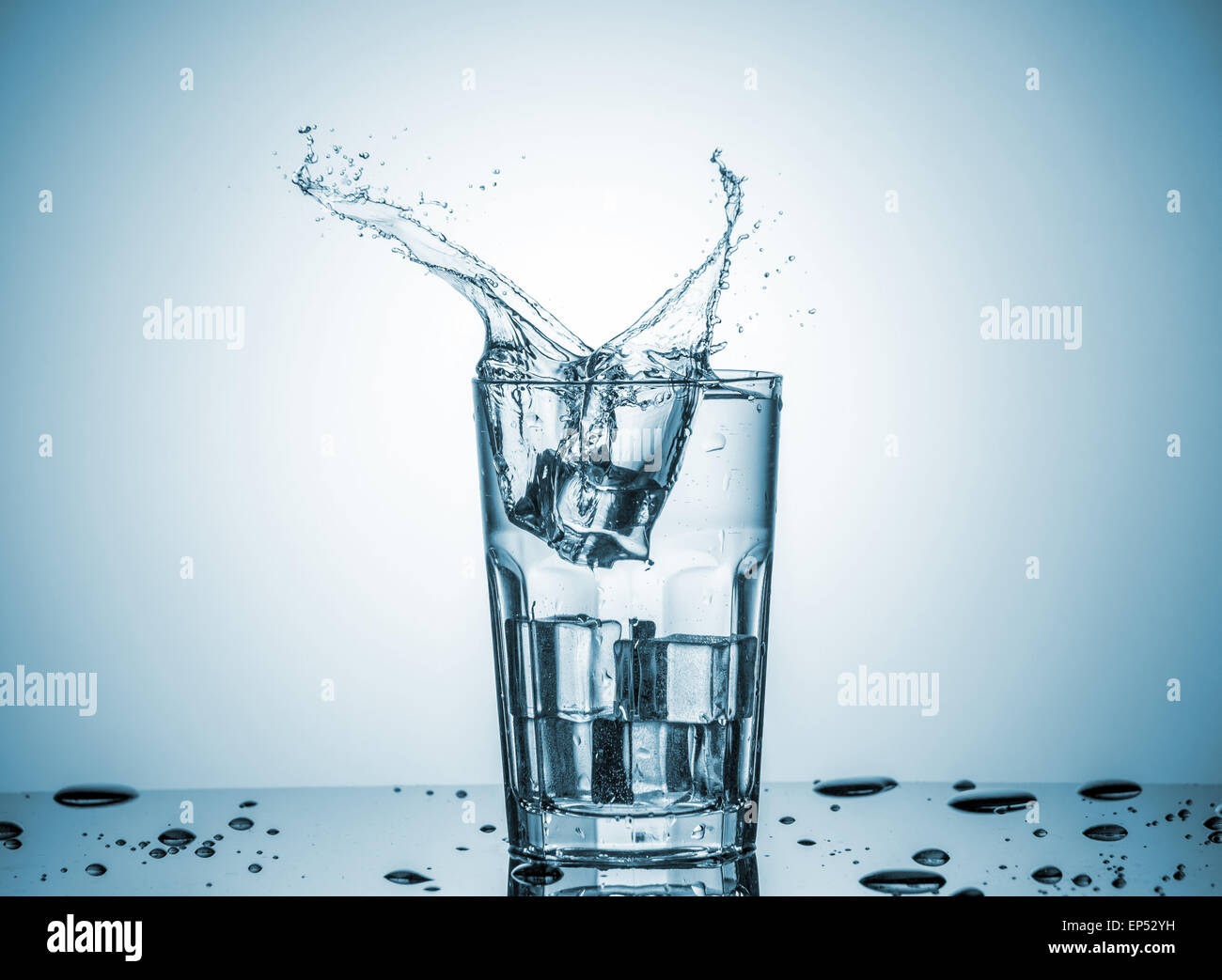 ice cubes falling into a glass of water on blue background Stock Photo ...