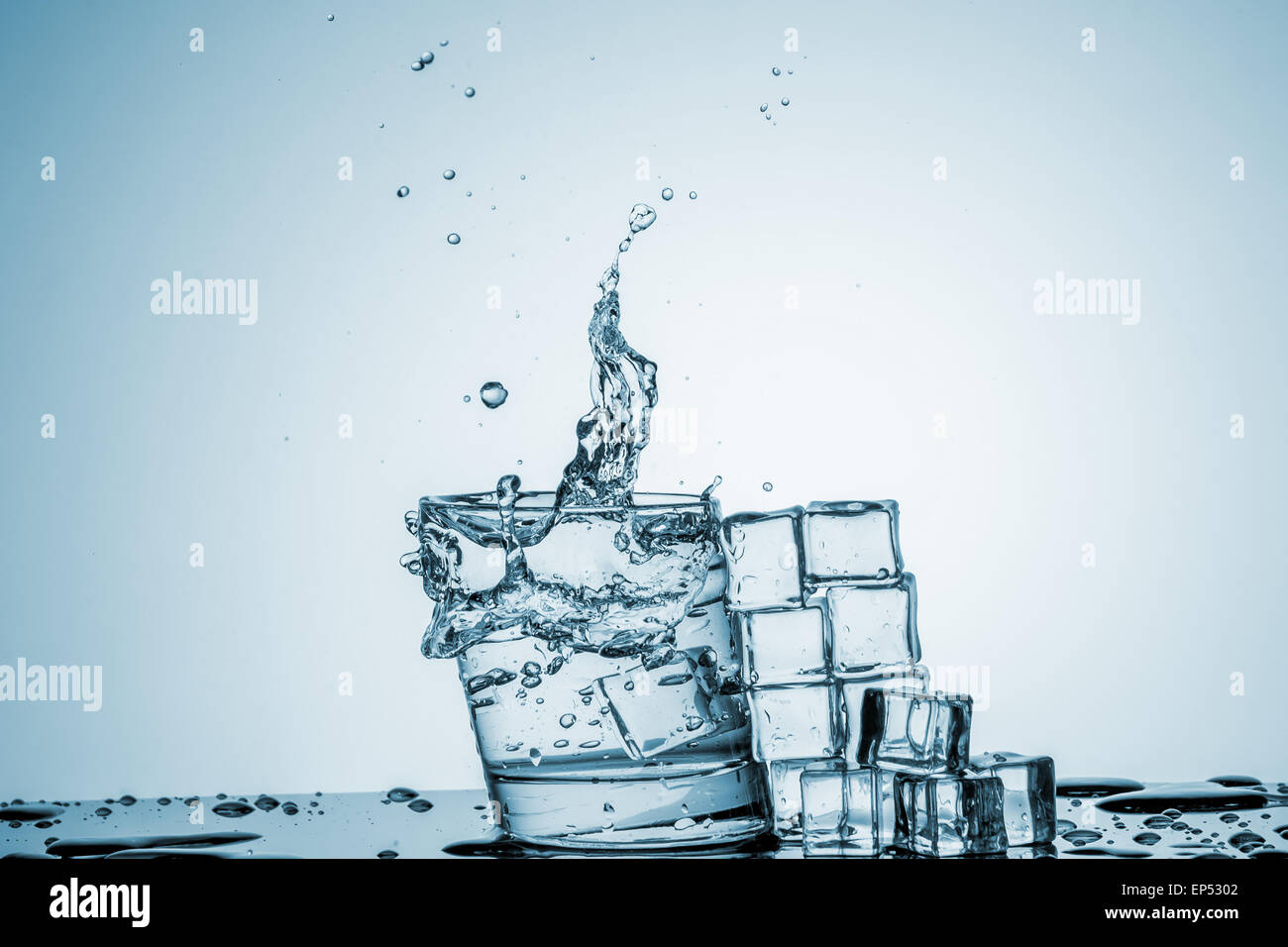 ice cubes falling into a glass of water and ice cubes, lying next, on ...