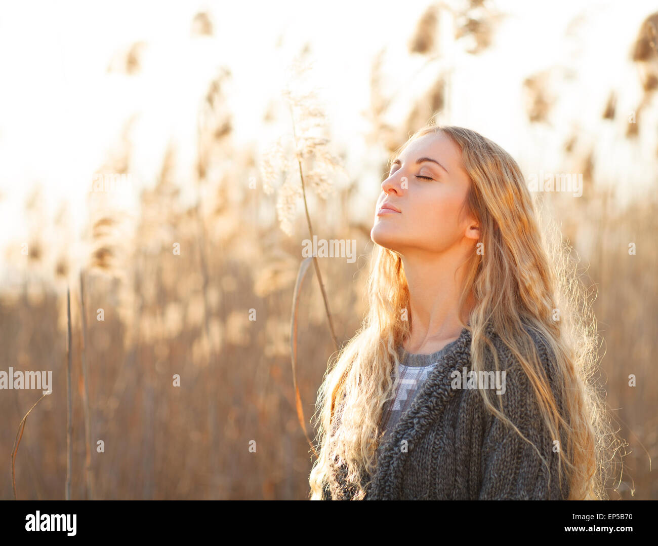 Portrait of a smiling blond woman relaxing outdoors Stock Photo - Alamy