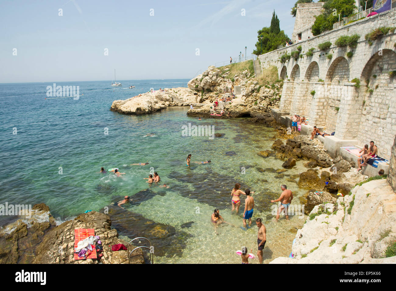 People swimming and sunbathing on the rocks of the city beach in Rovinj ...