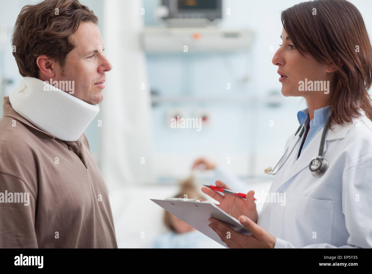 Doctor talking to a male patient with a collar on Stock Photo - Alamy